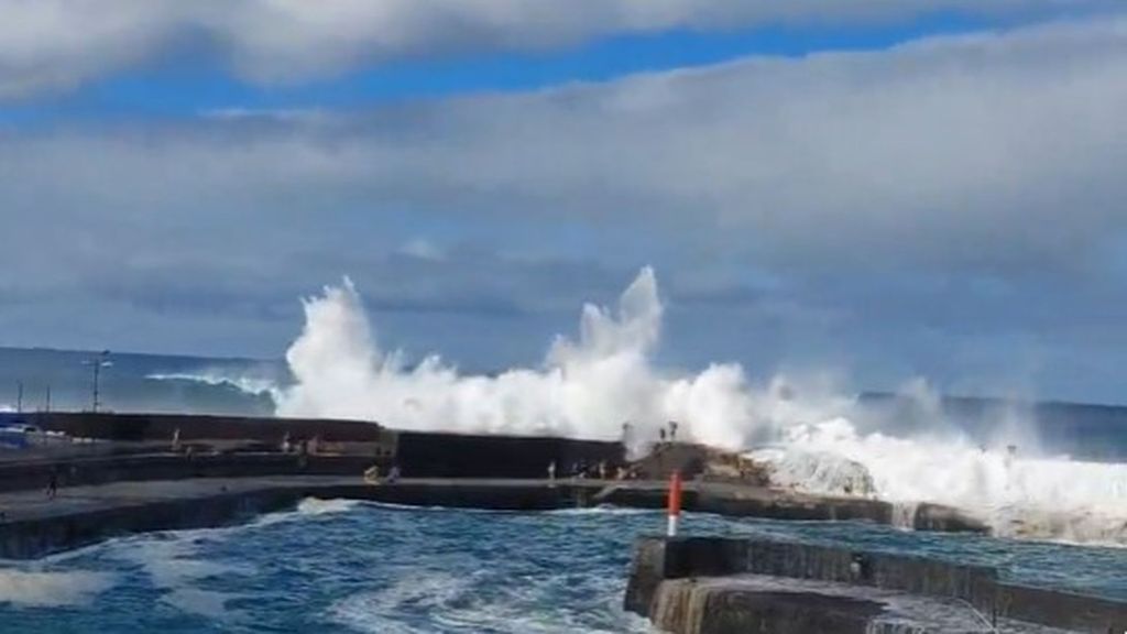 Momento en que un golpe de mar arrastra a varias personas en el muelle ...